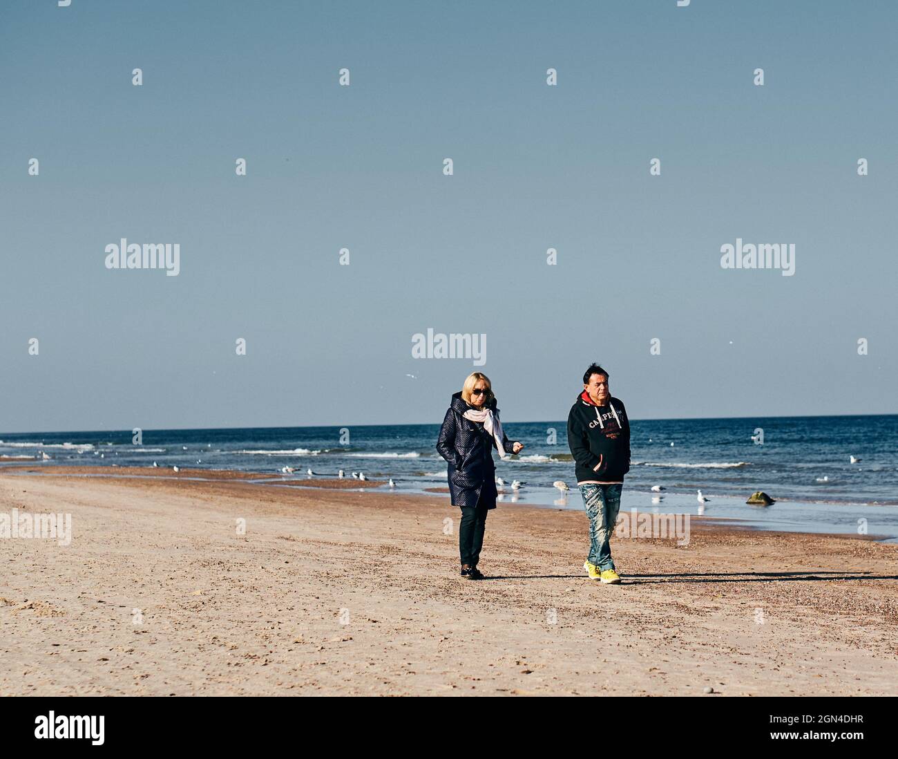 SARBINOWO, POLAND - Oct 16, 2017: A man and woman walking on sand close ...