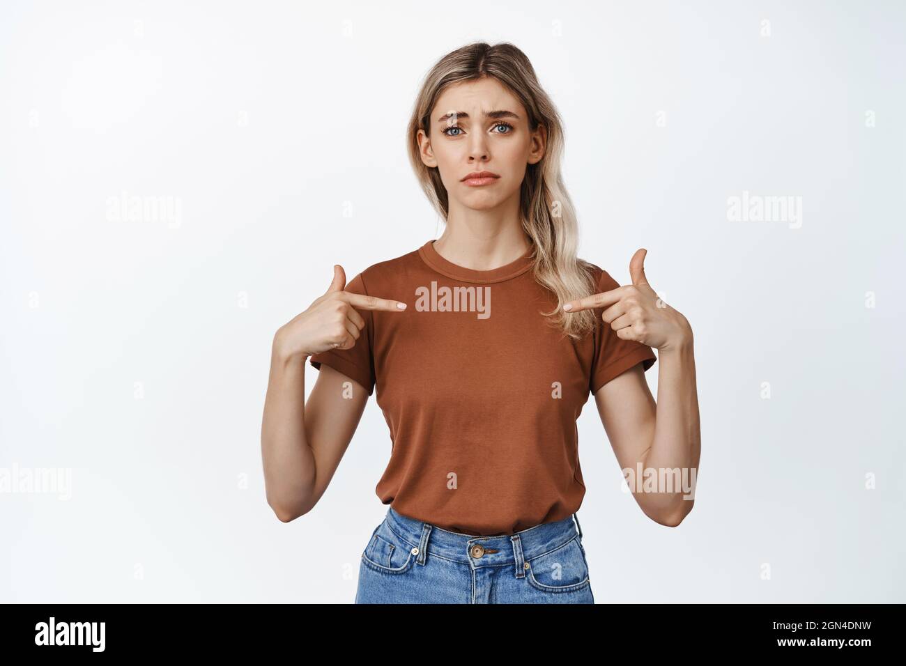 Sad blond girl pointing fingers at herself and looking miserable ...