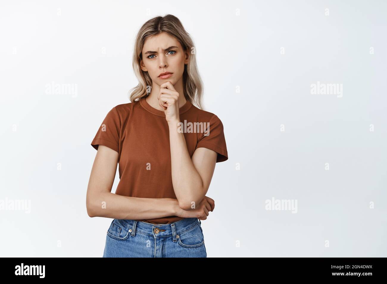 Thoughtful serious woman frowning, touching chin and looking concerned ...