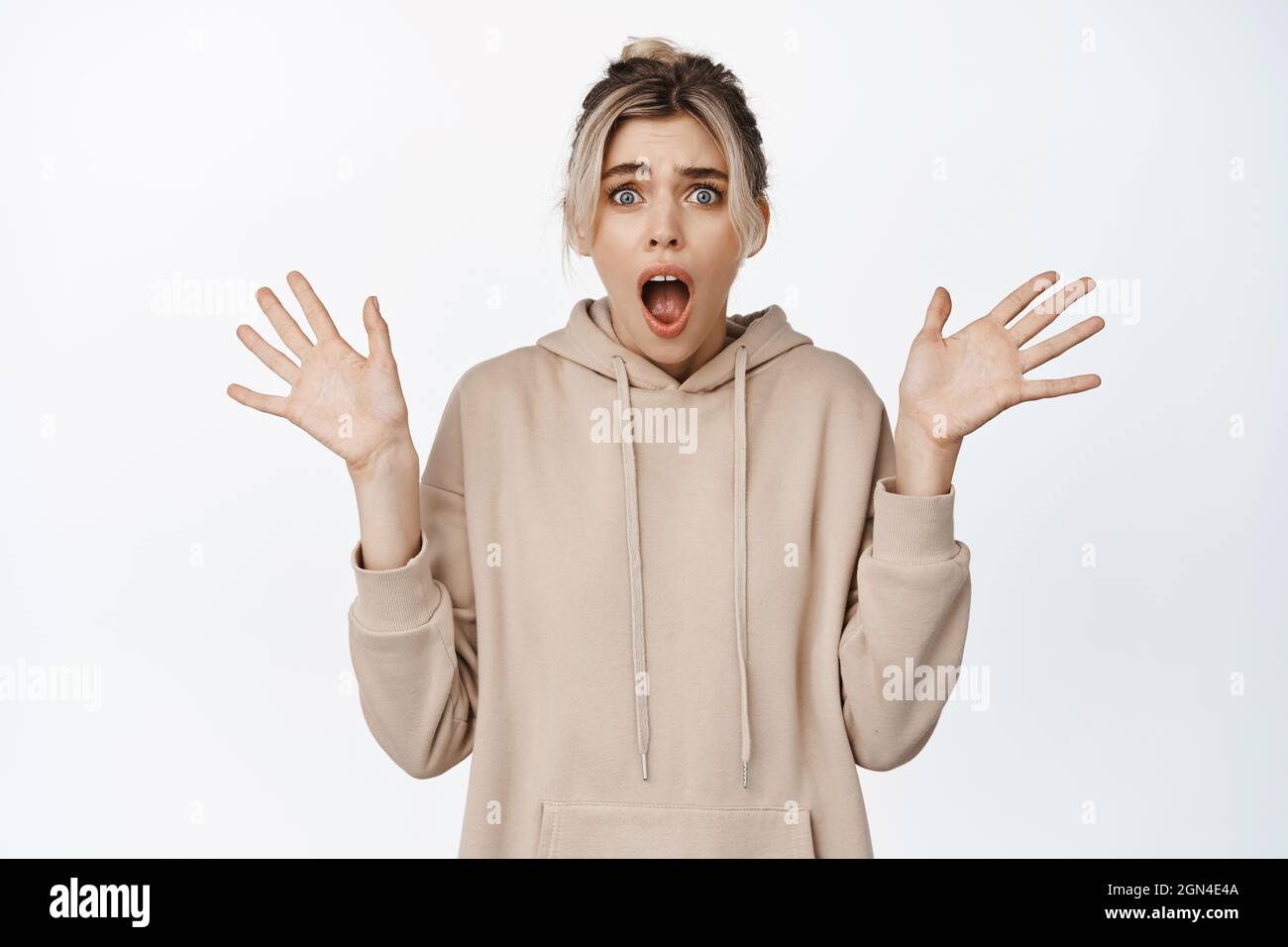 Young blond girl screams and looks anxious, shaking hands in panic ...