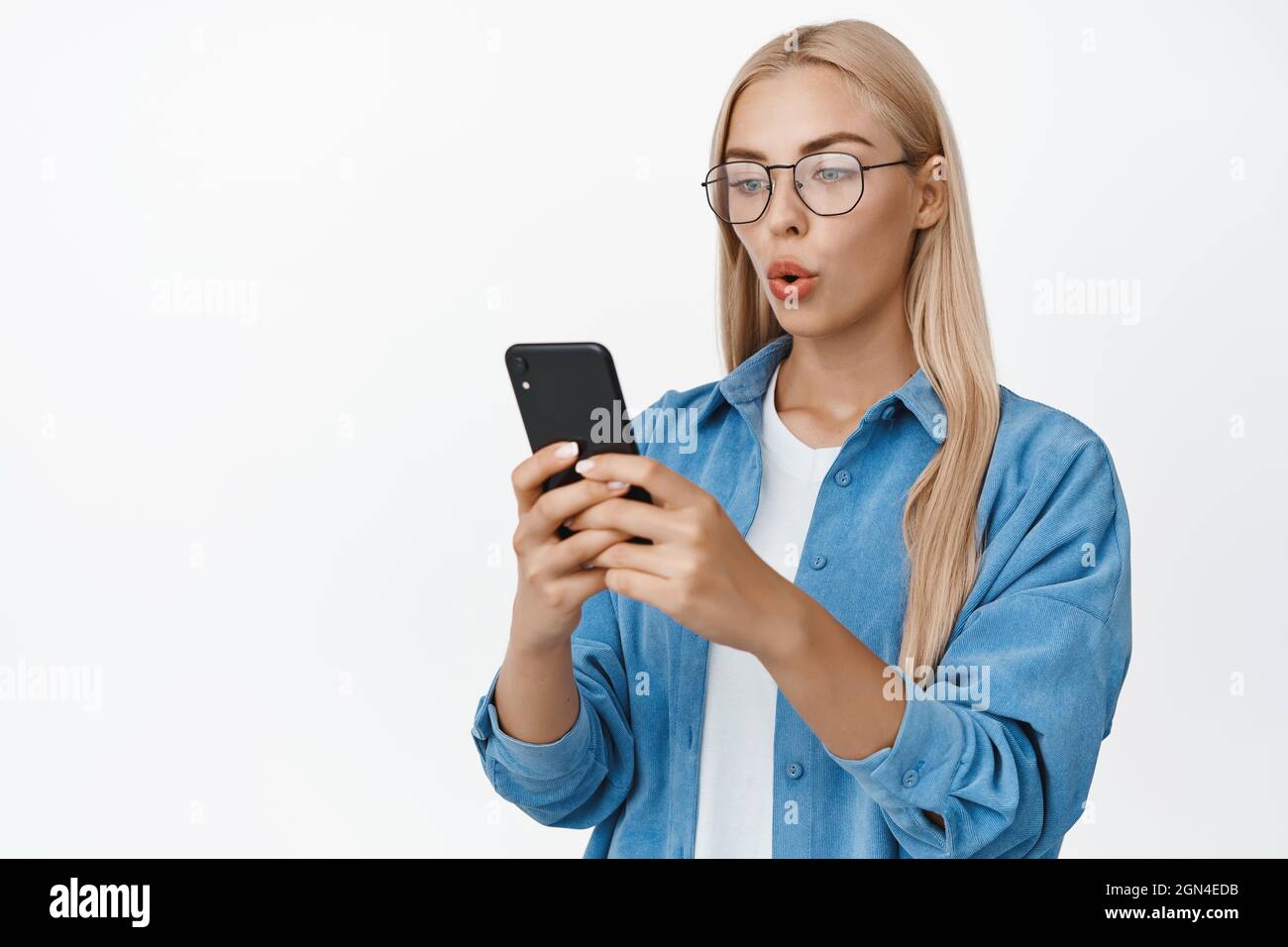 Portrait of young female student in glasses looking at her mobile phone ...