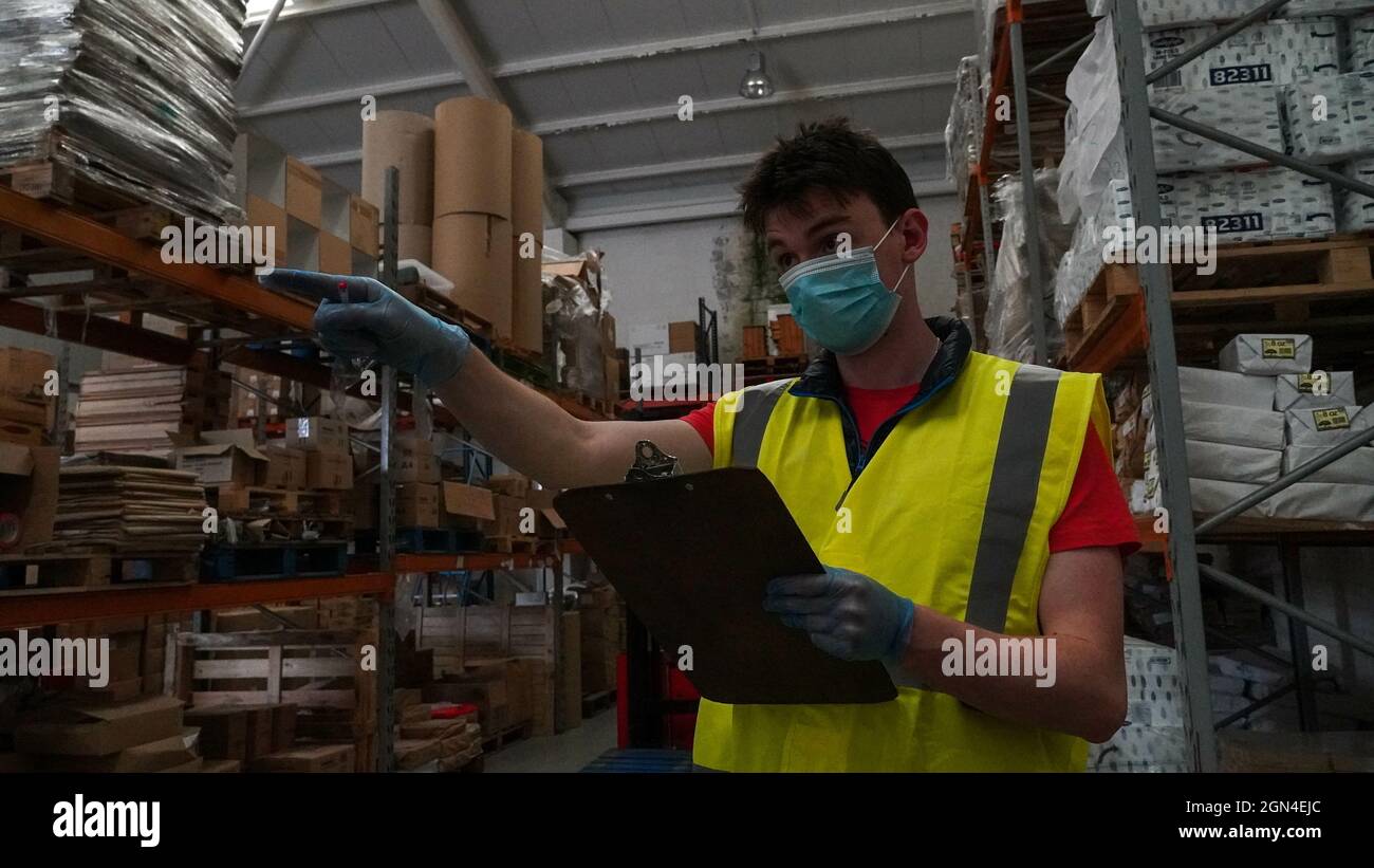 Male warehouse worker in a medical face mask with a clipboard Stock ...