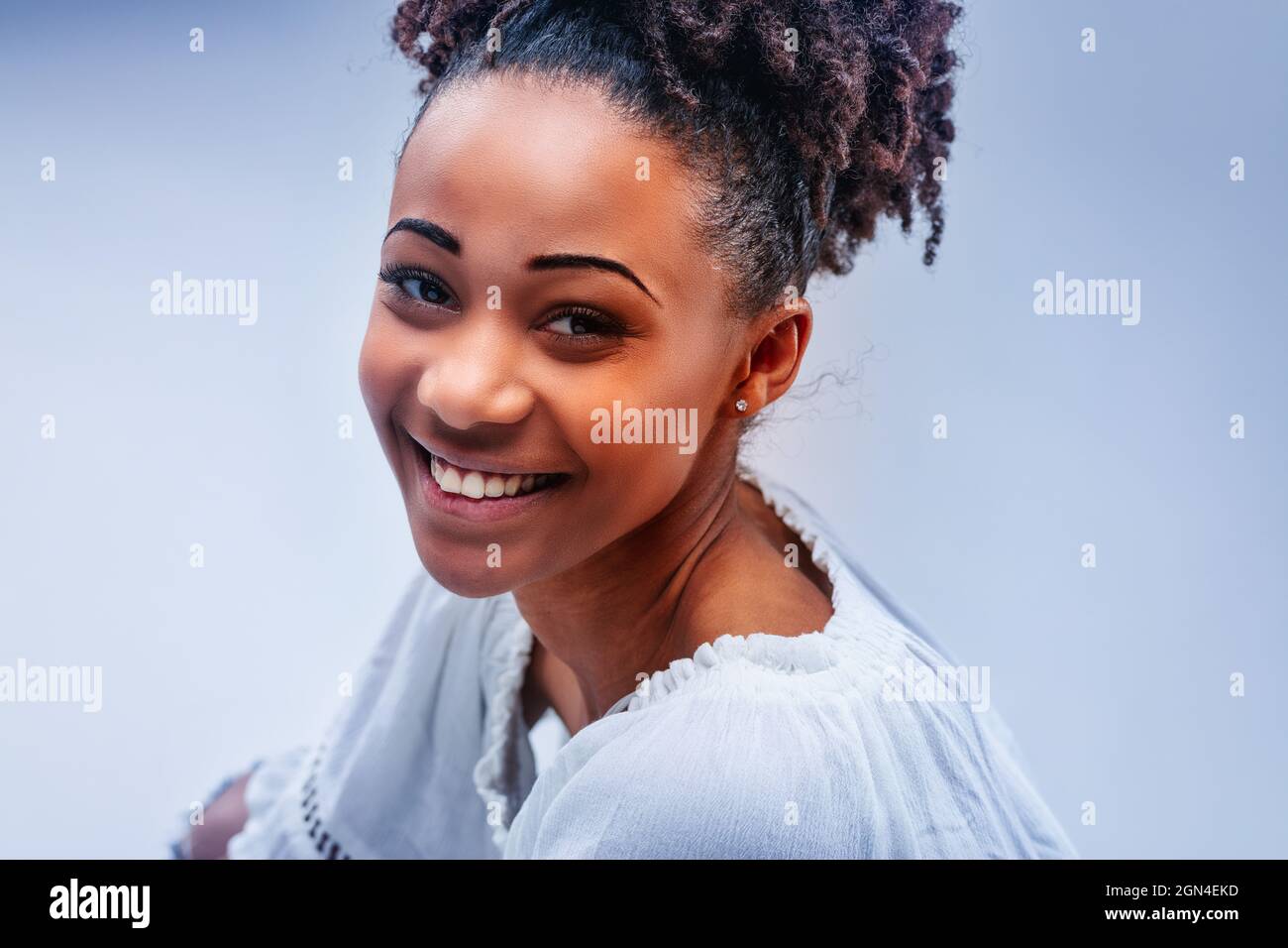 Happy beautiful young Black woman with a beaming smile turning to look ...