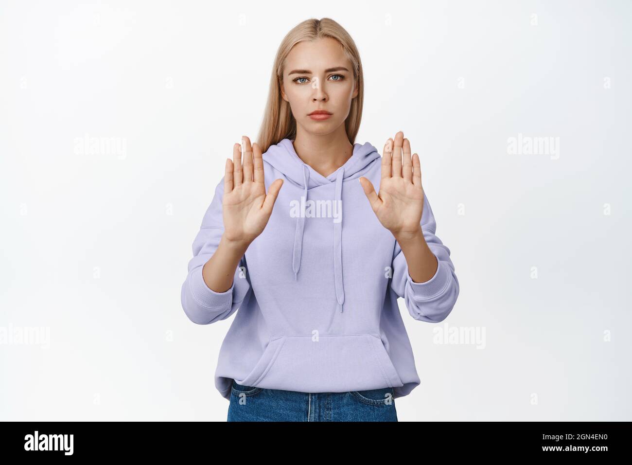 Serious young blond woman push you back, showing stop, no gesture ...