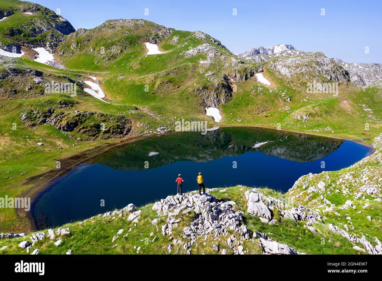 Aerial view of 2 hikers above alpine lake manito in the in Moraca ...