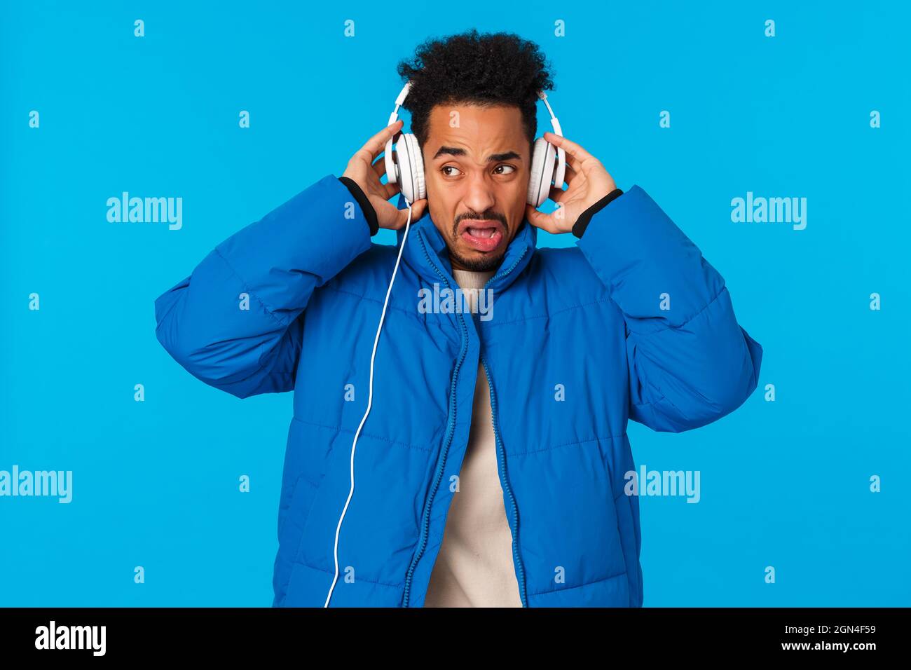 Cringing and bothered african-american man grimacing hearing bad sound ...