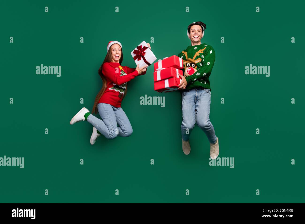 Photo of crazy funky couple jump hold present box wear santa hat ugly ...