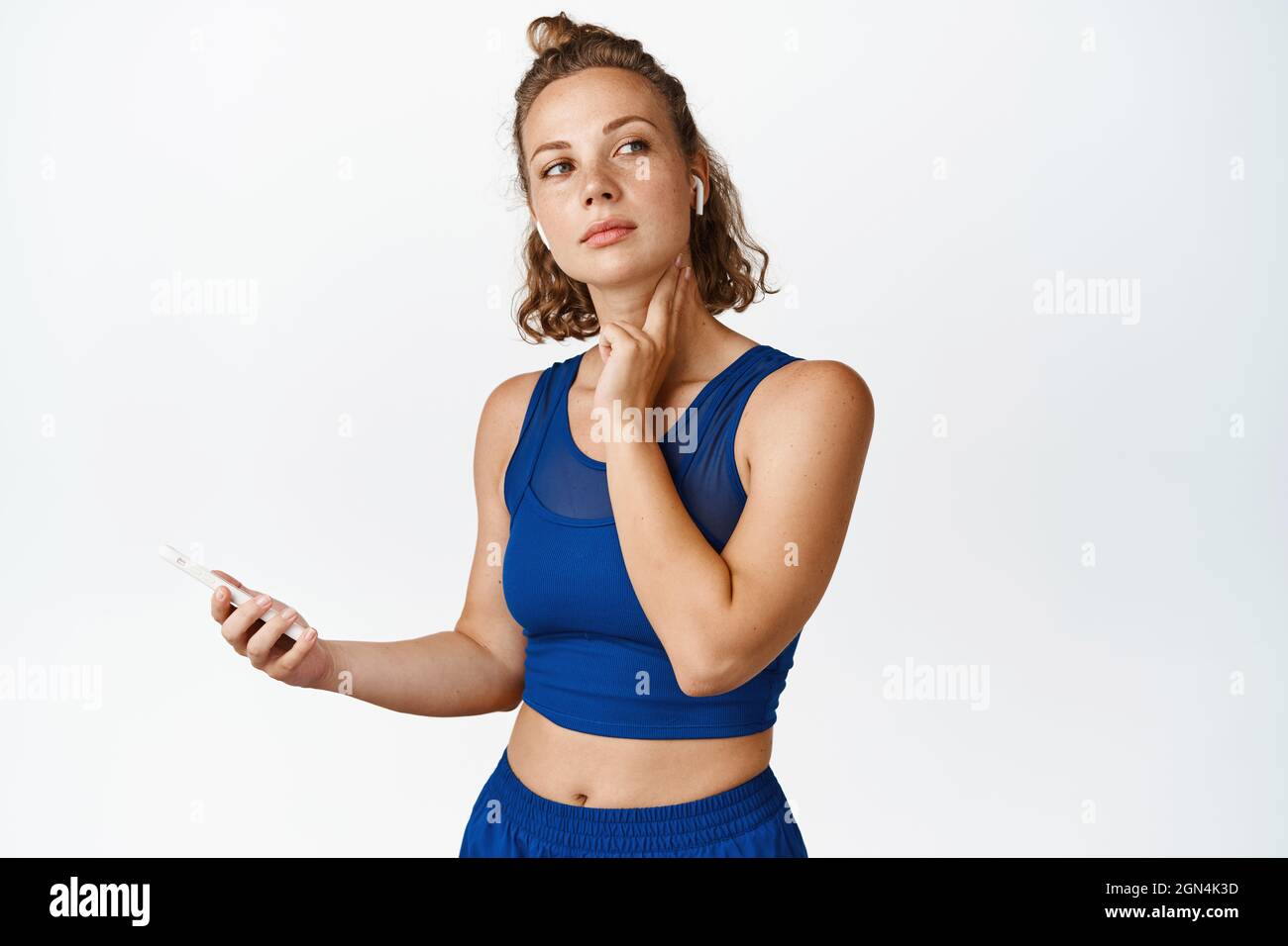 Young fitness woman checking pulse on her neck, using mobile app to ...