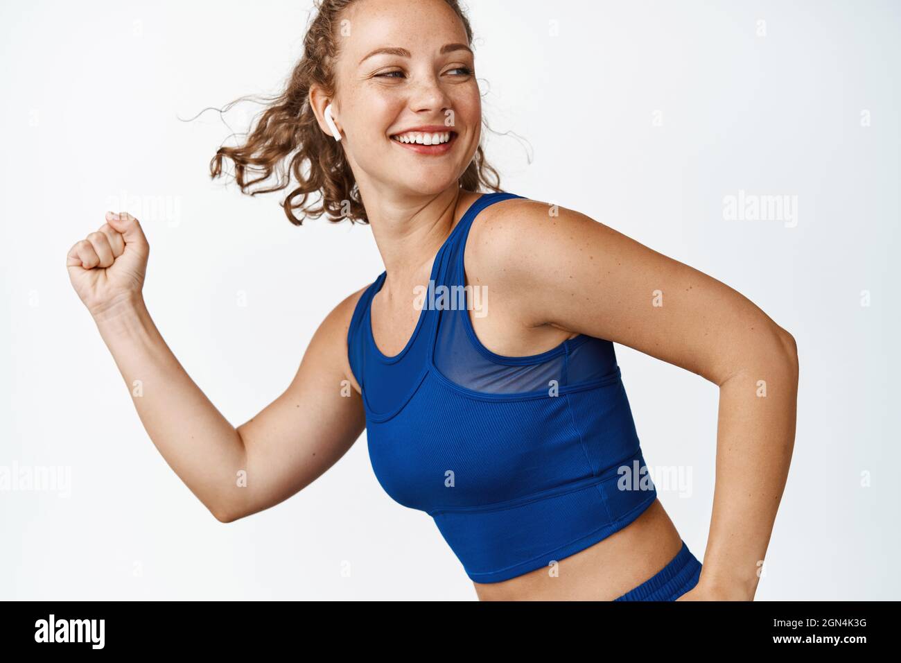 Close up portrait of happy fitness woman running, looking behind her ...
