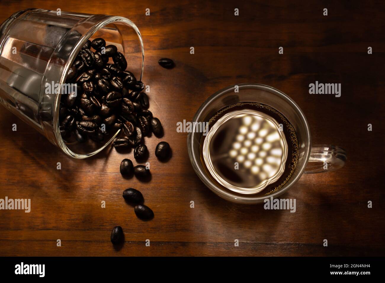 A transparent cup full of coffee and a glass with fallen coffee beans ...