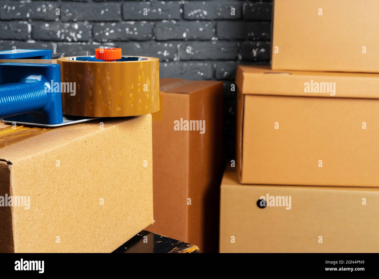 Stack of cardboard boxes in the empty room against black brick wall ...