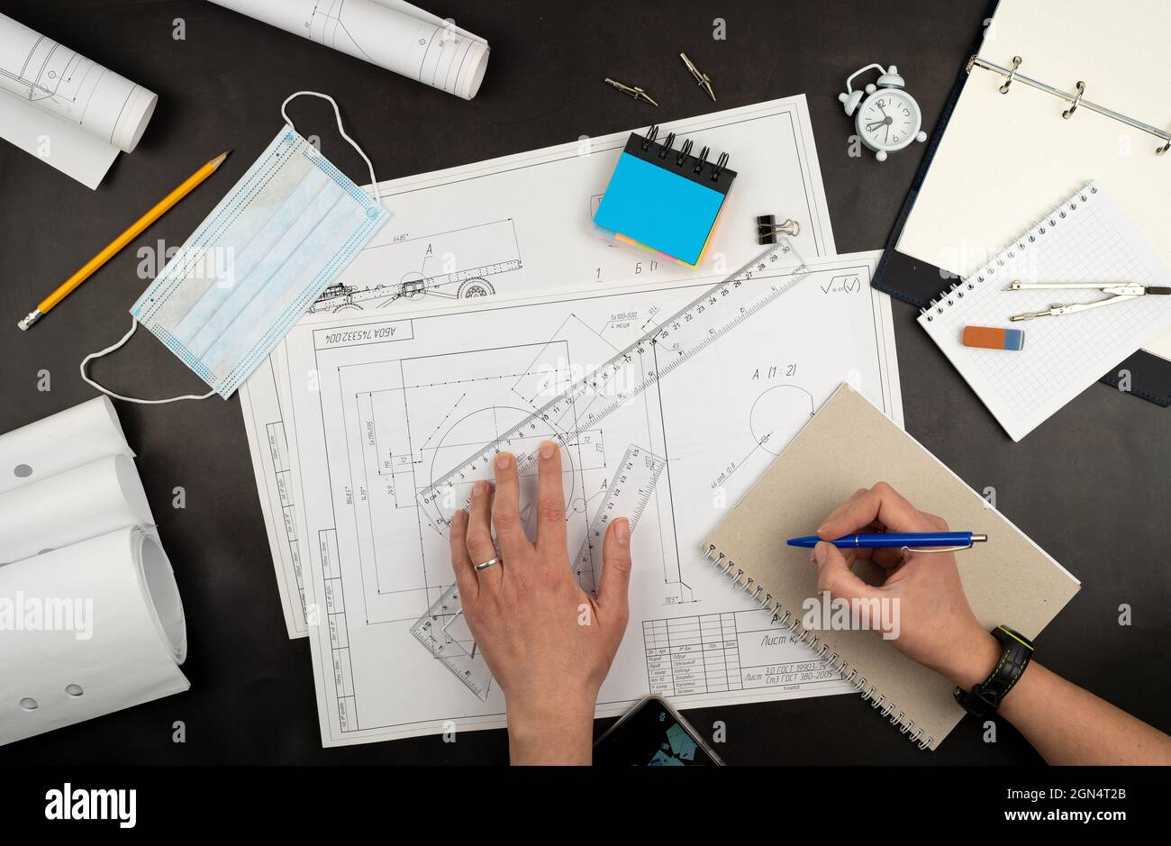 Mechanical drawing on sheets of paper. Hands on the table top view ...