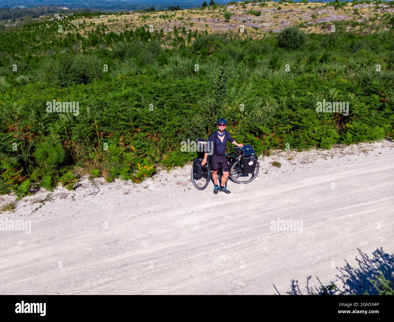 View of a person wearing cycling attire standing next to the bike on the ground covered in snow ...