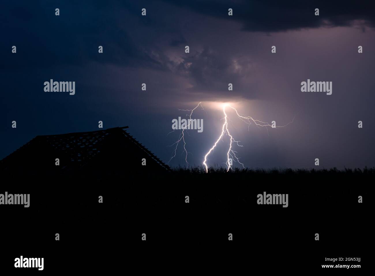 Lightning strikes behind a barn in the countryside in eastern Europe ...