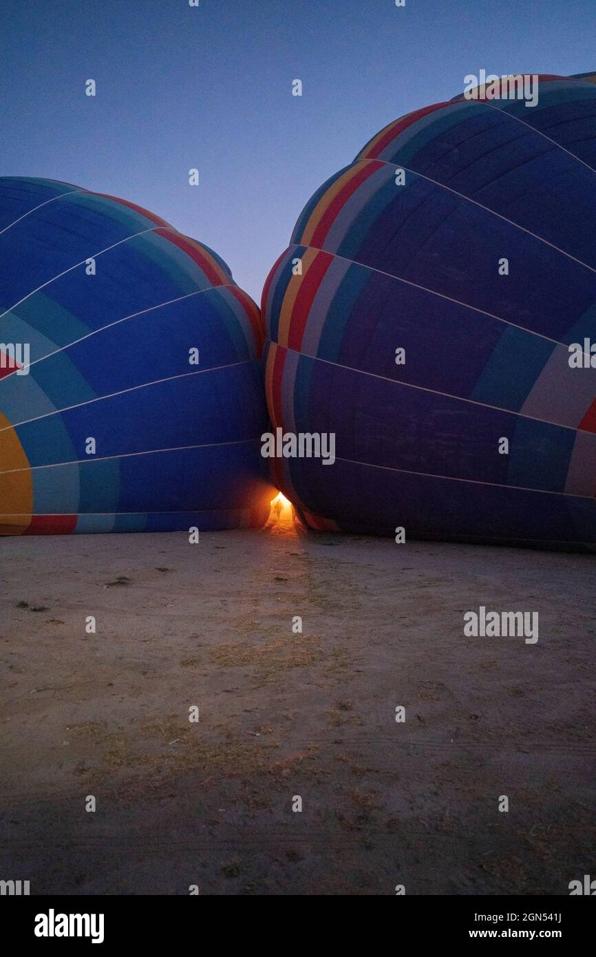 A crew standing in between the two partially filled hot air balloon or ...