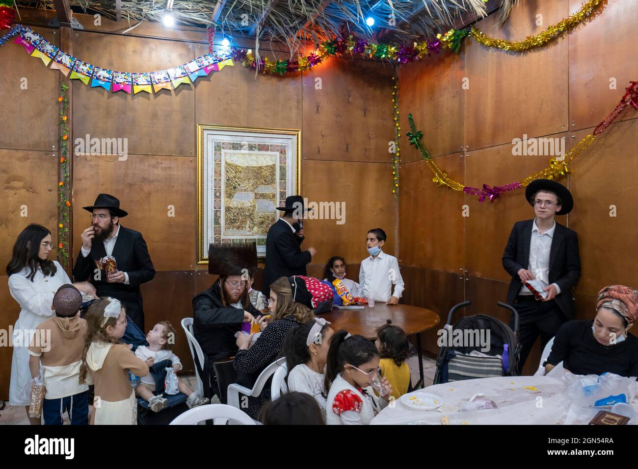 Religious Jews sit inside a traditional wooden sukkah temporary hut ...