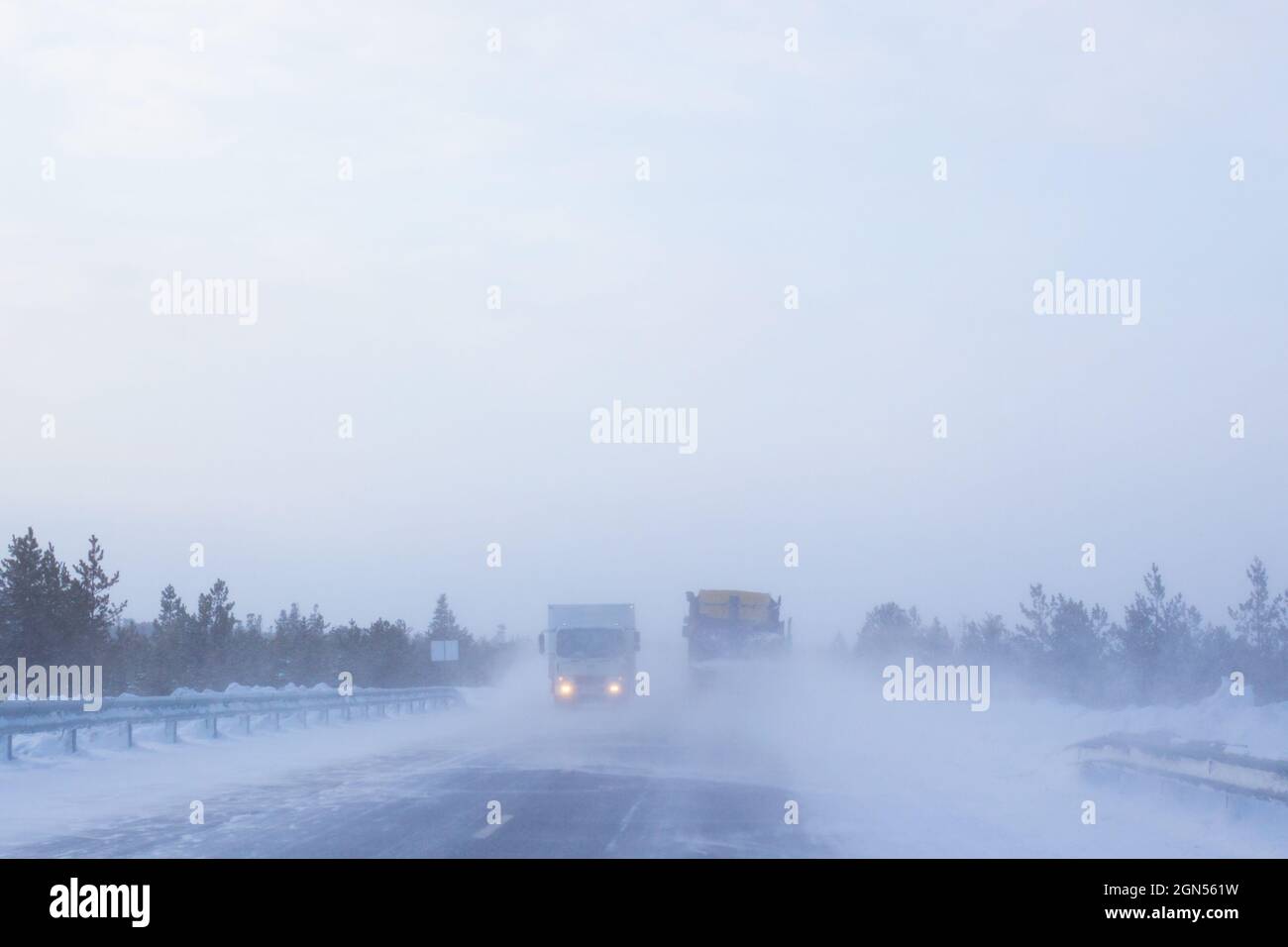cars go on a winter road with poor visibility, weather and snowstorm ...