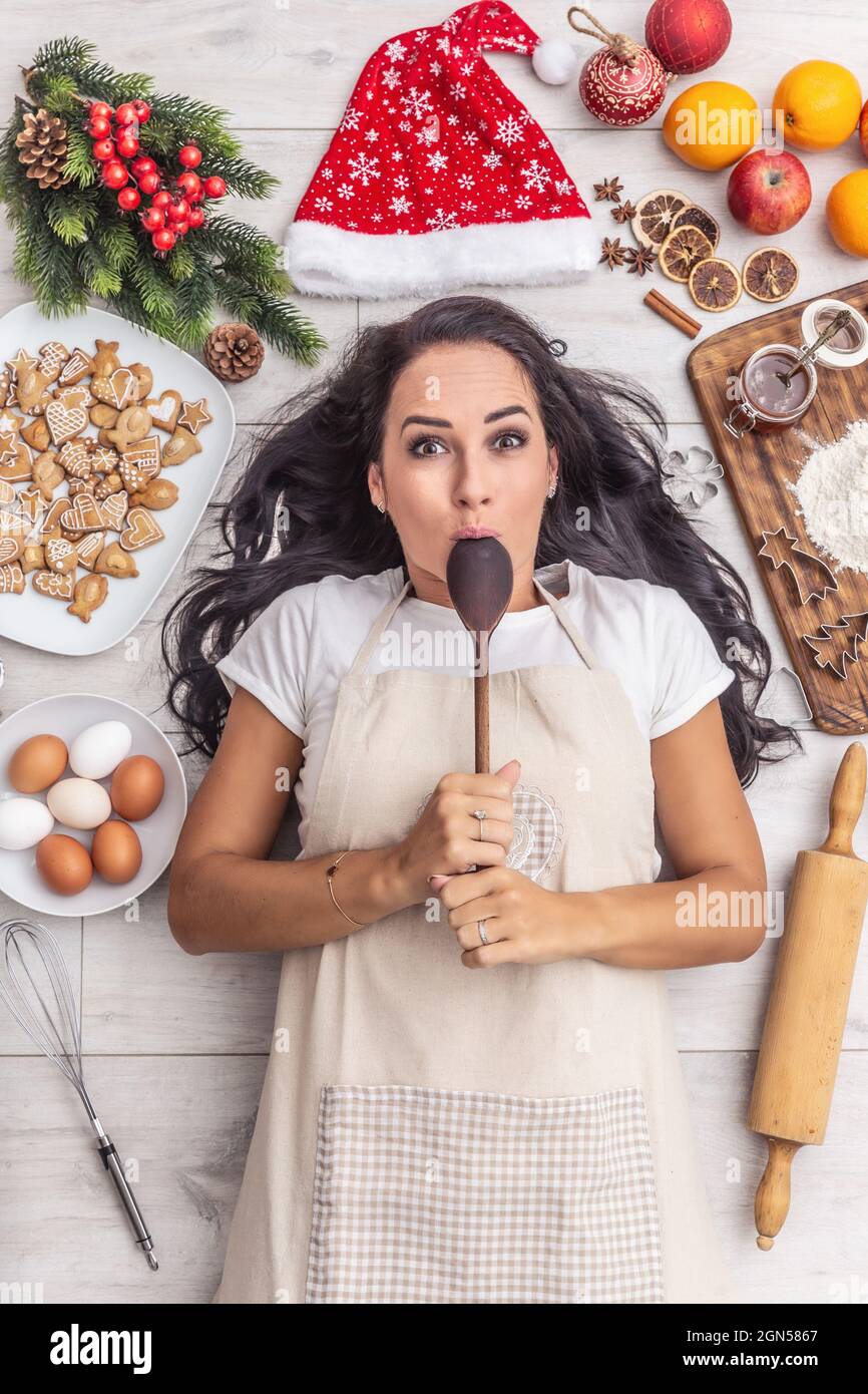 Good-looking dark haired cook biting the wooden spoon and laying on the ...