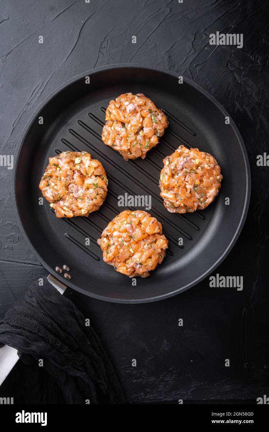 Raw fish patties with salmon fillet and lemongrass, on black textured ...