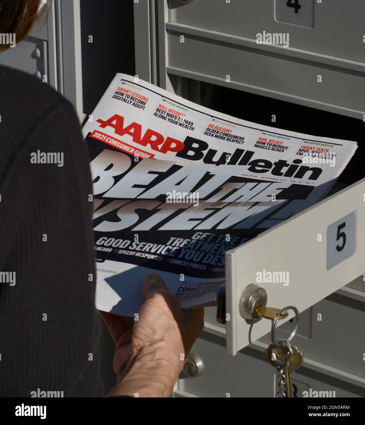 Aarp Bulletin Logo A Woman Removes Her Mail, Including A Copy Of The