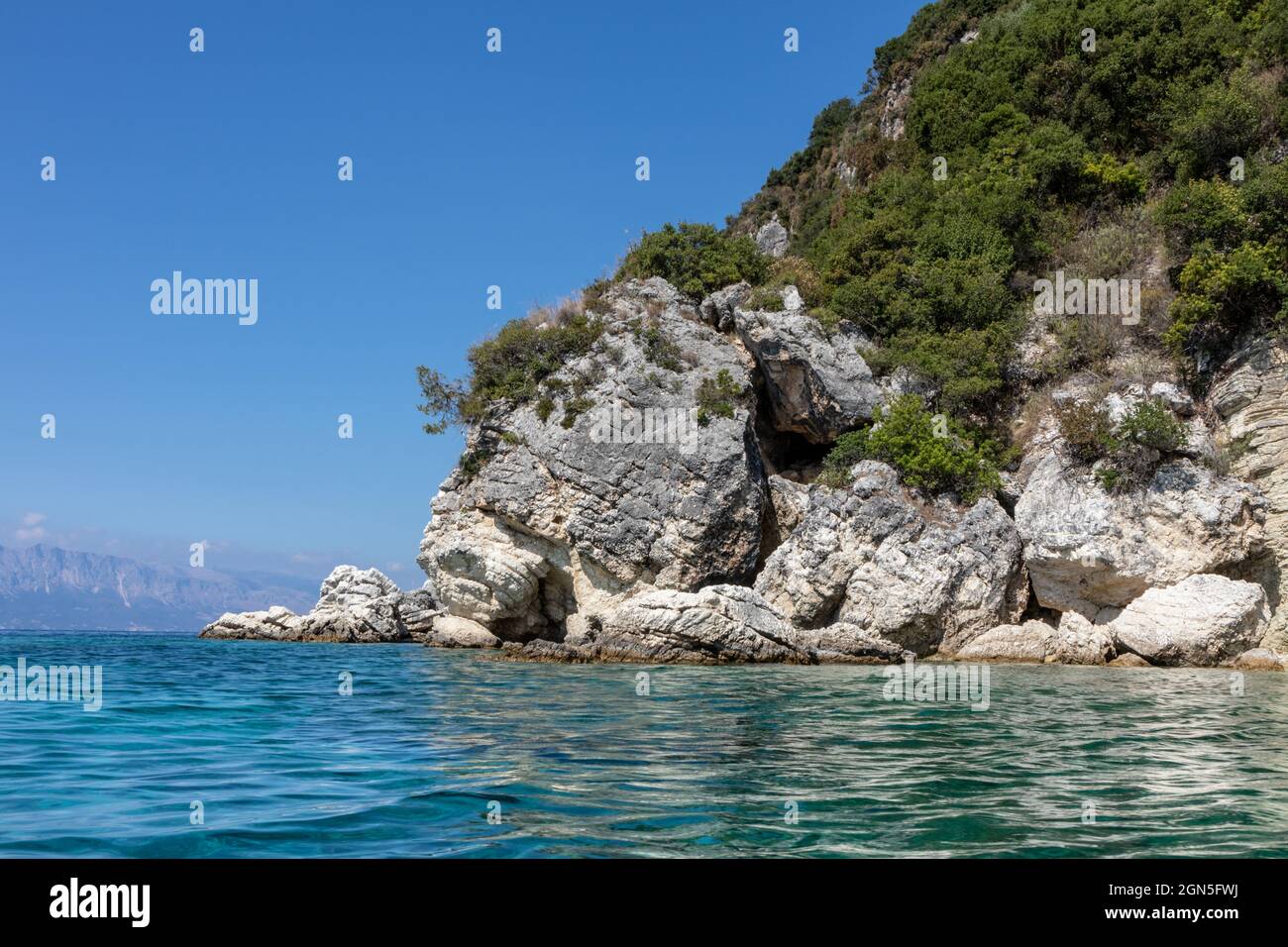Scenic rocks in blue water of Ionian Sea with green cliffs and bright ...