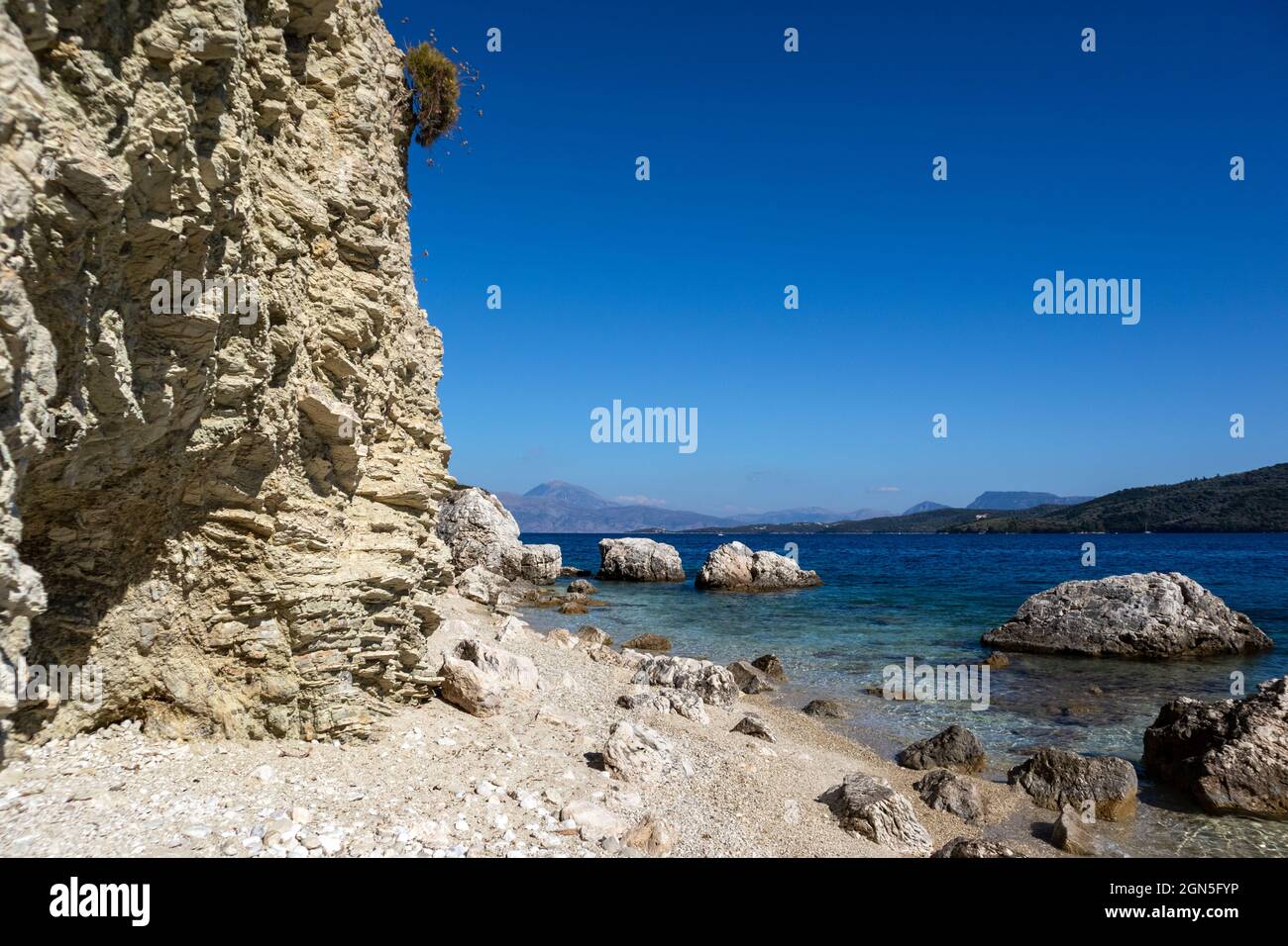 White rocky cliffs on pebble beach with blue clear water on coast of ...