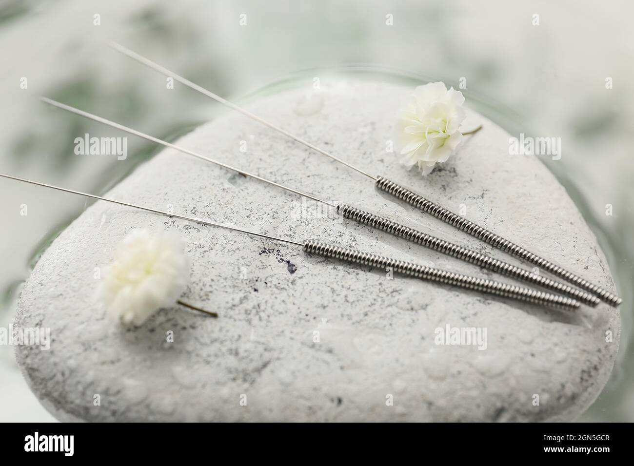 Acupuncture needles and spa stone on water, closeup Stock Photo - Alamy