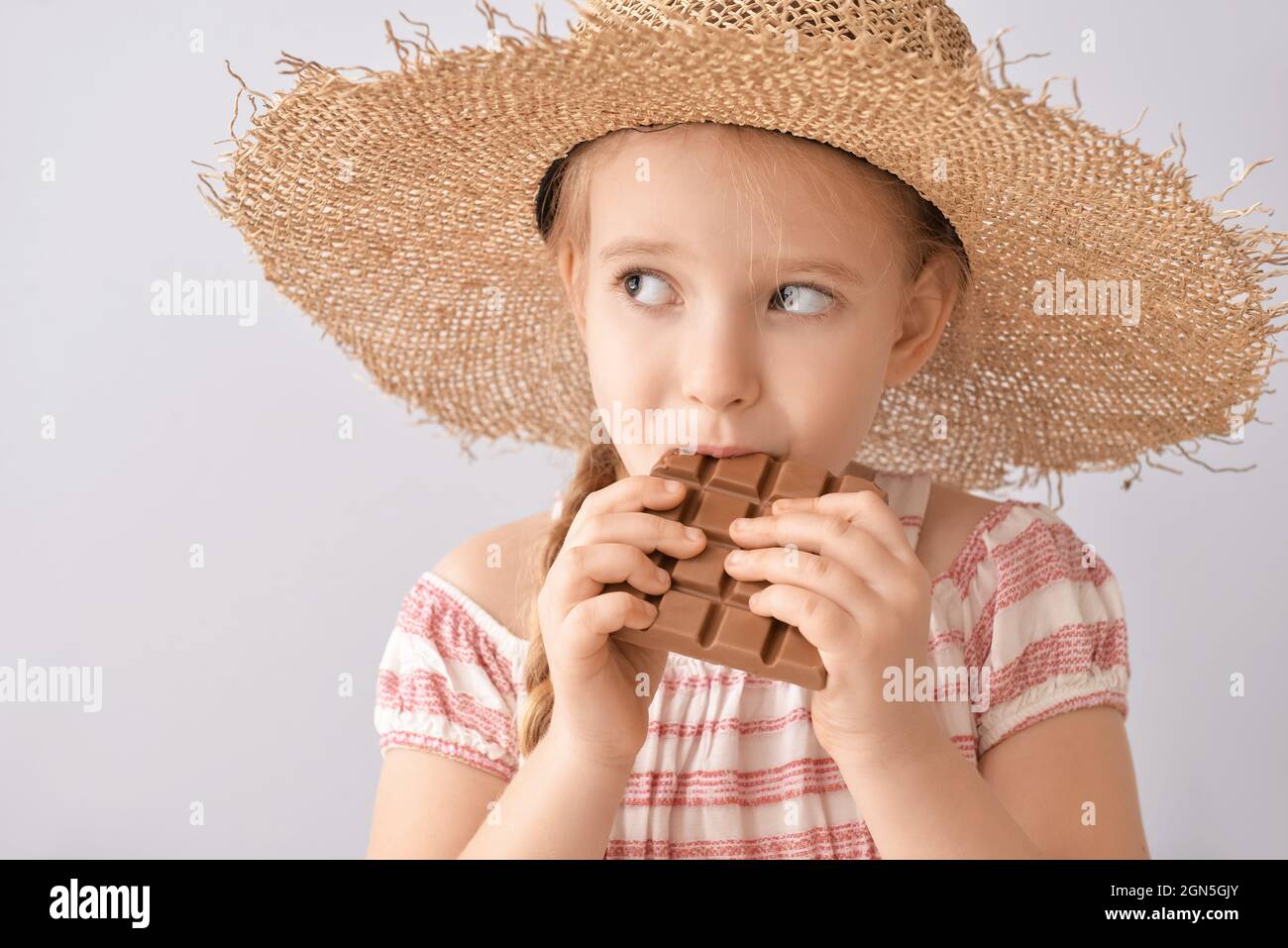 Cute little girl eating chocolate on light background, closeup Stock ...