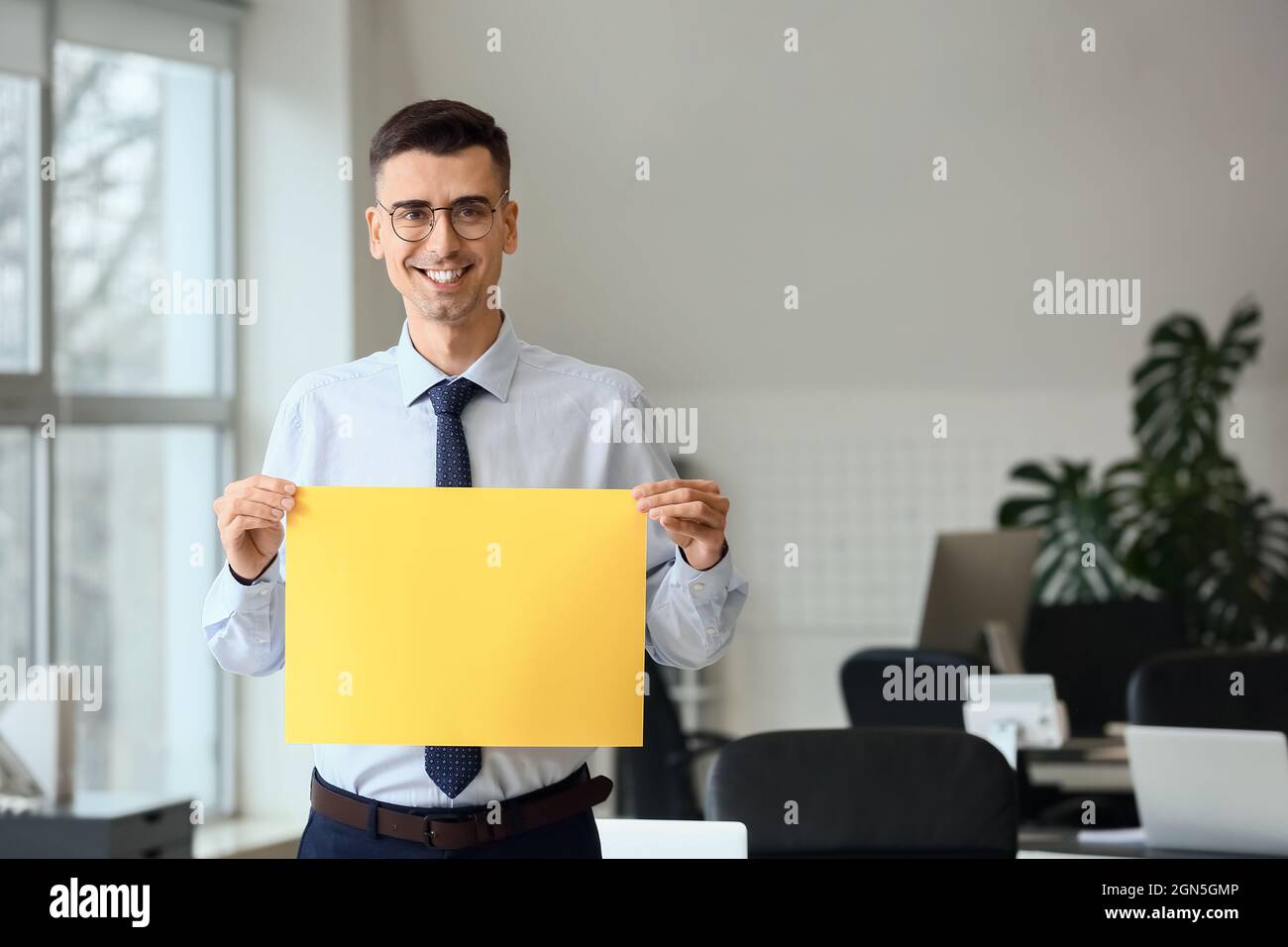 Young man with blank paper sheet in office Stock Photo - Alamy