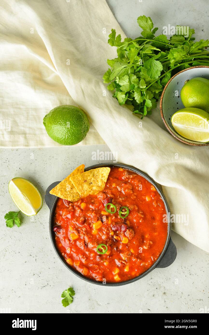 Frying pan with delicious chili con carne, nachos and lime on light ...