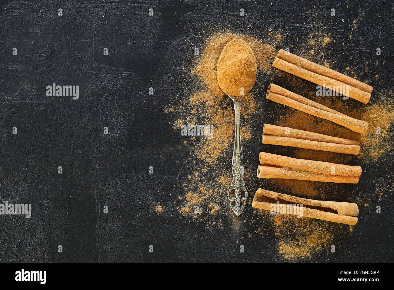 Cinnamon sticks and spoon on black background, top view Stock Photo - Alamy