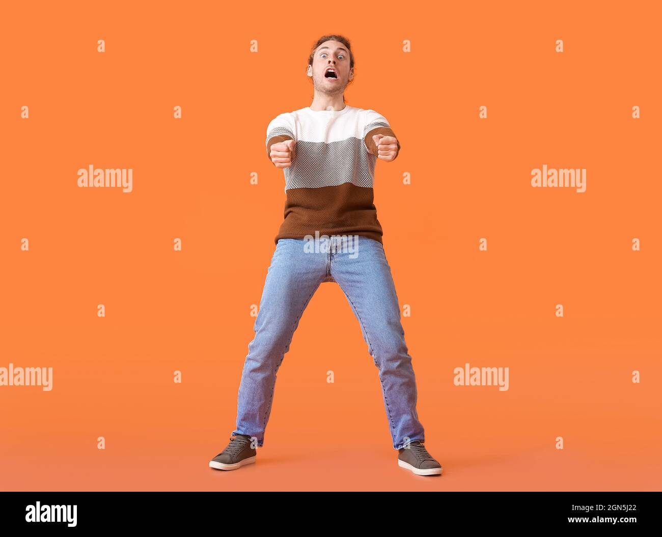 Shocked young man with imaginary steering wheel on color background ...