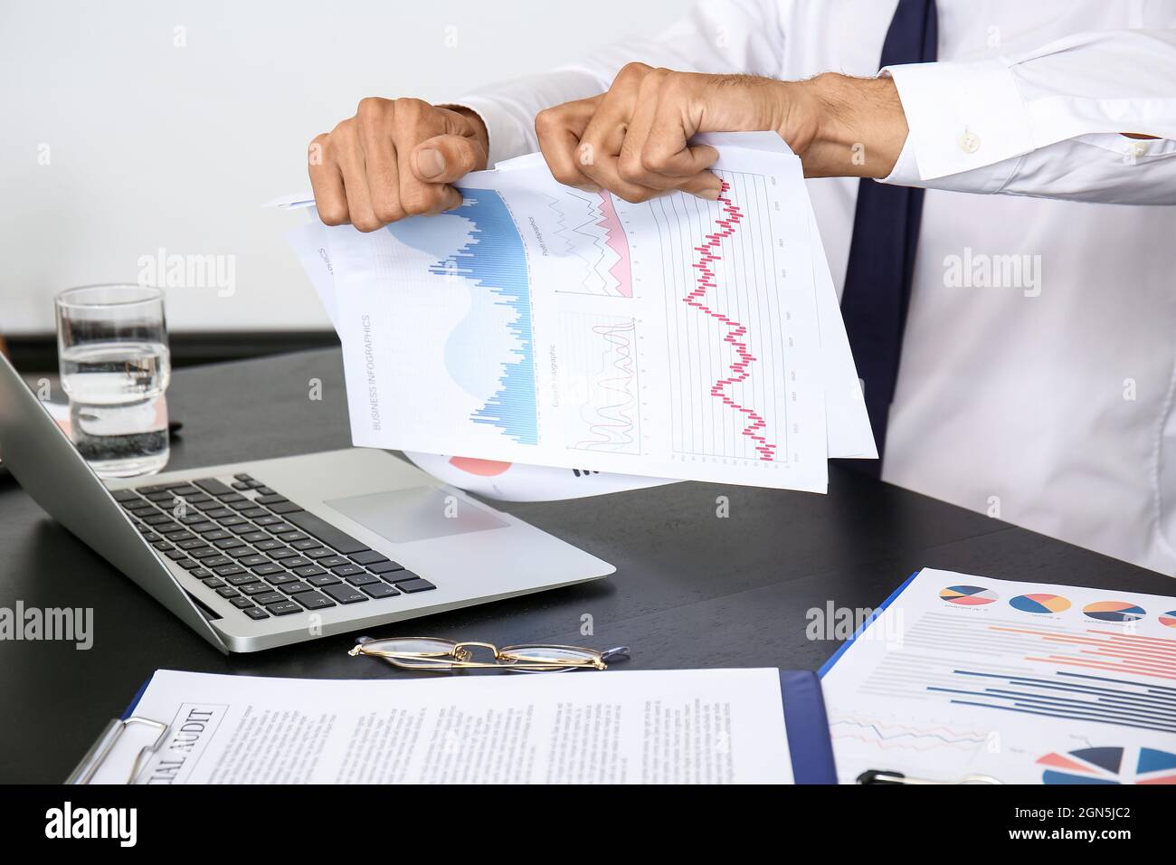 Stressed businessman tearing charts at table in office Stock Photo - Alamy