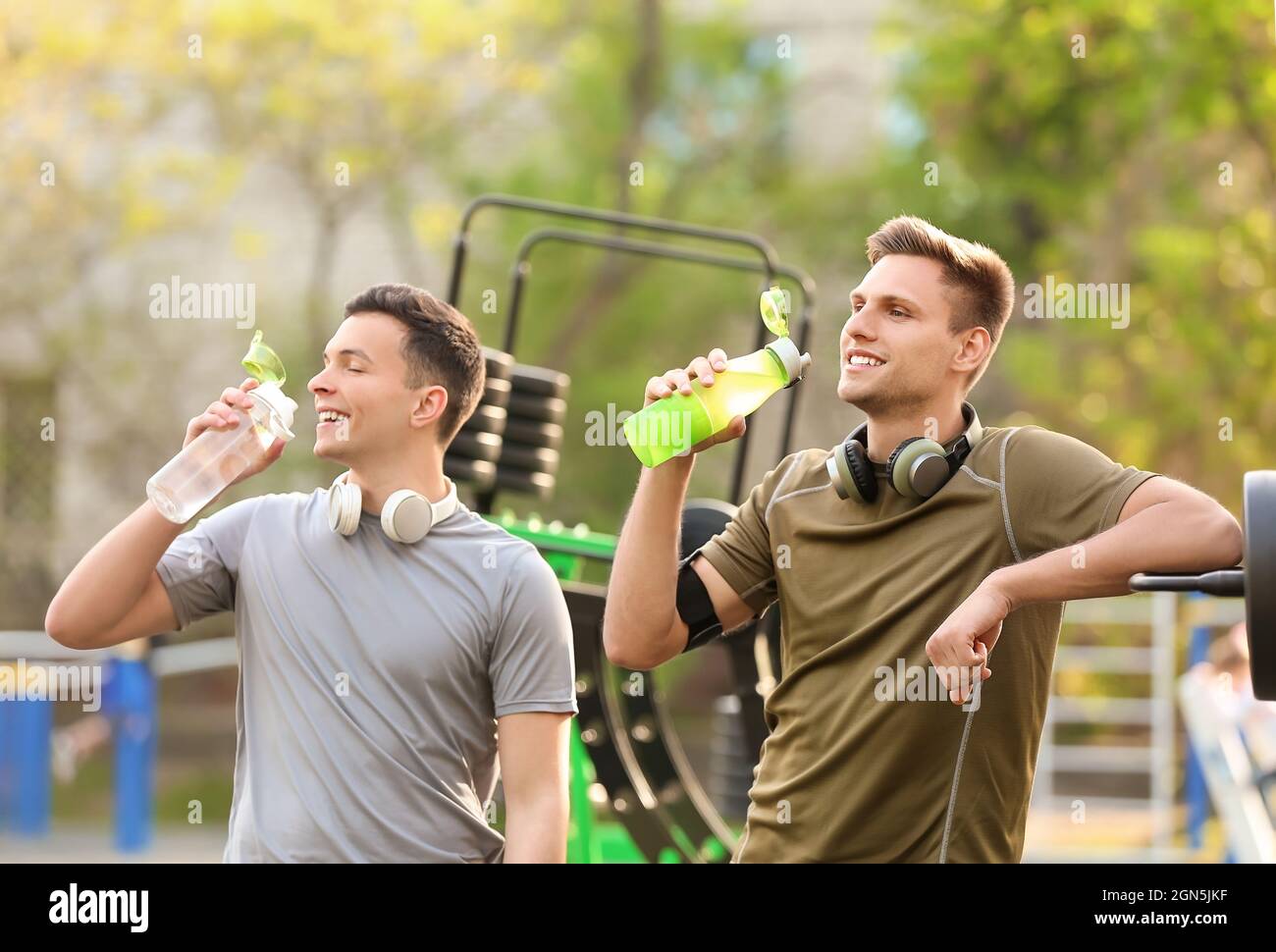 Young men drinking water on sport ground Stock Photo - Alamy