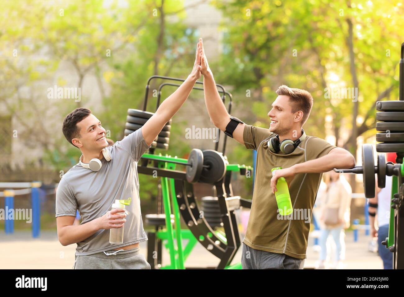 Young men giving each other high-five on sport ground Stock Photo - Alamy