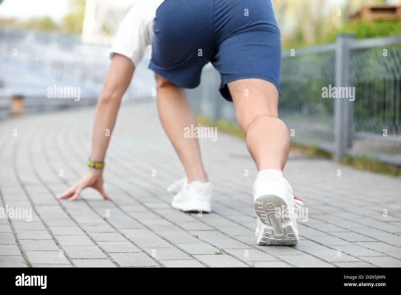 Sporty young man getting ready to run at stadium Stock Photo - Alamy