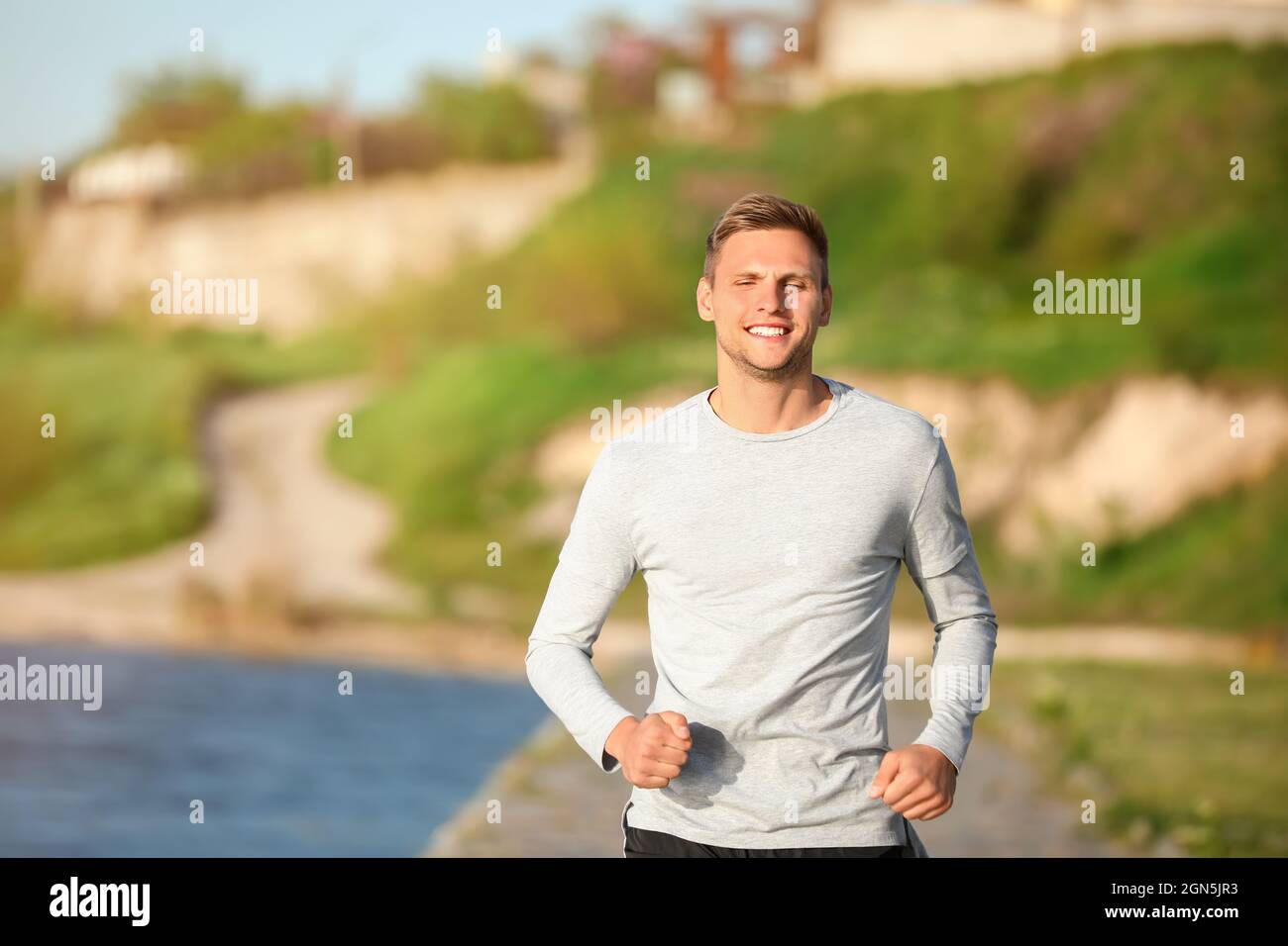 Sporty young man jogging near river Stock Photo - Alamy