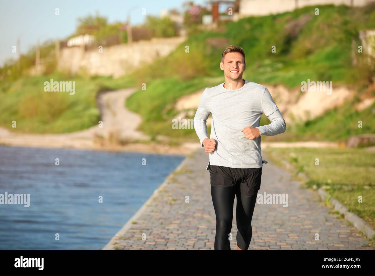 Sporty young man jogging near river Stock Photo - Alamy