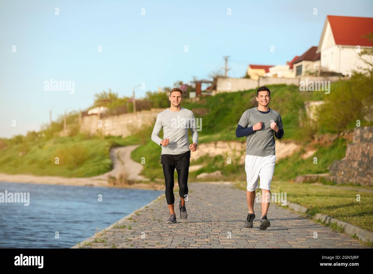 Sporty young men running near river Stock Photo - Alamy