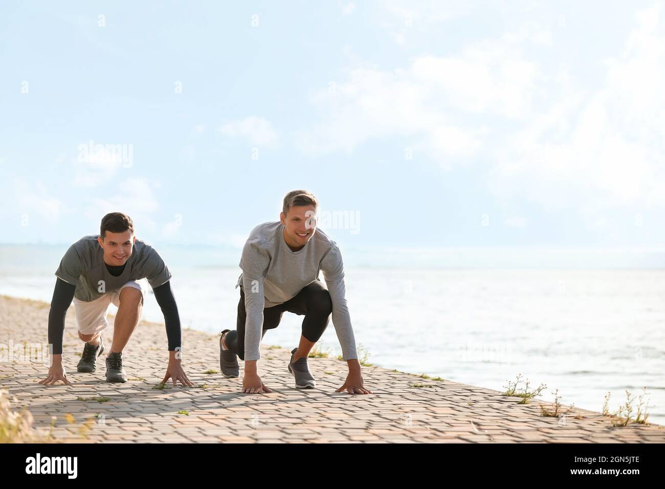 Sporty young men getting ready to run near river Stock Photo - Alamy