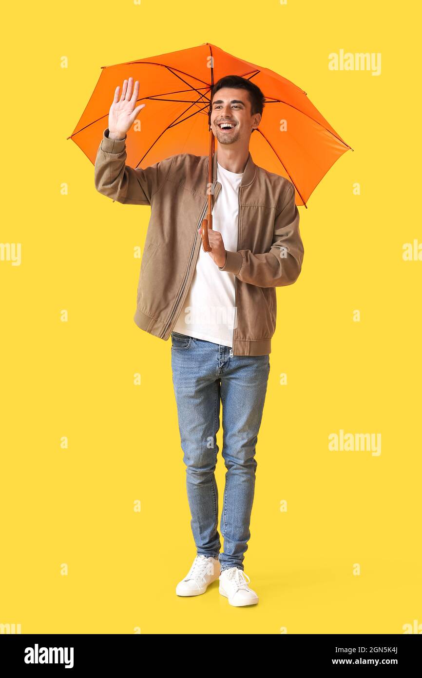 Handsome young man with umbrella on color background Stock Photo - Alamy