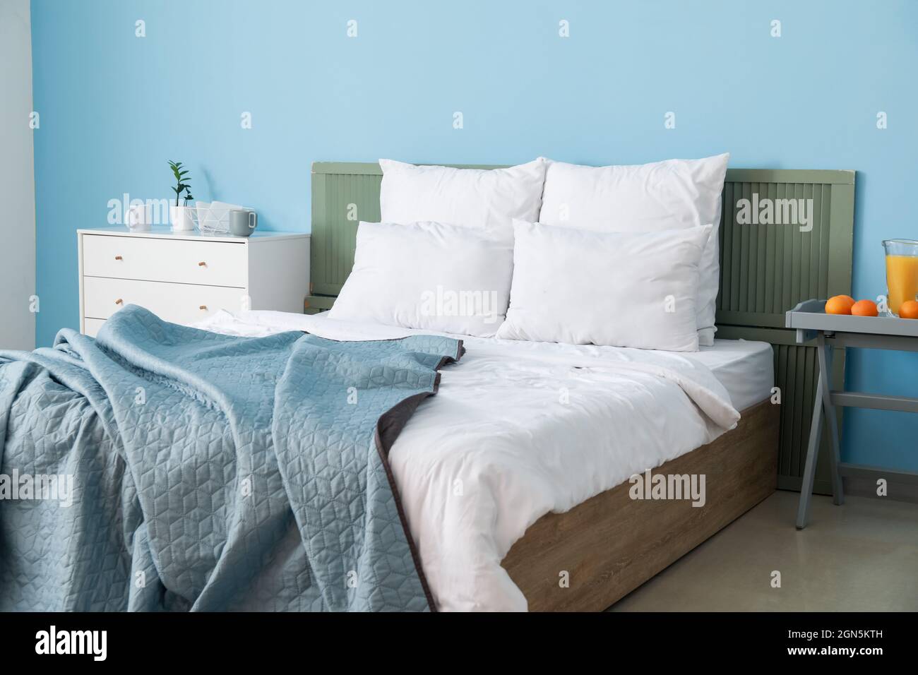 Comfy bed near color wall in interior of modern bedroom Stock Photo - Alamy