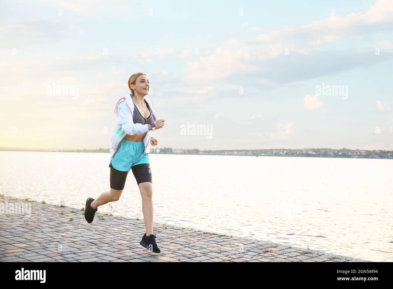 Sporty mature woman running near river Stock Photo - Alamy