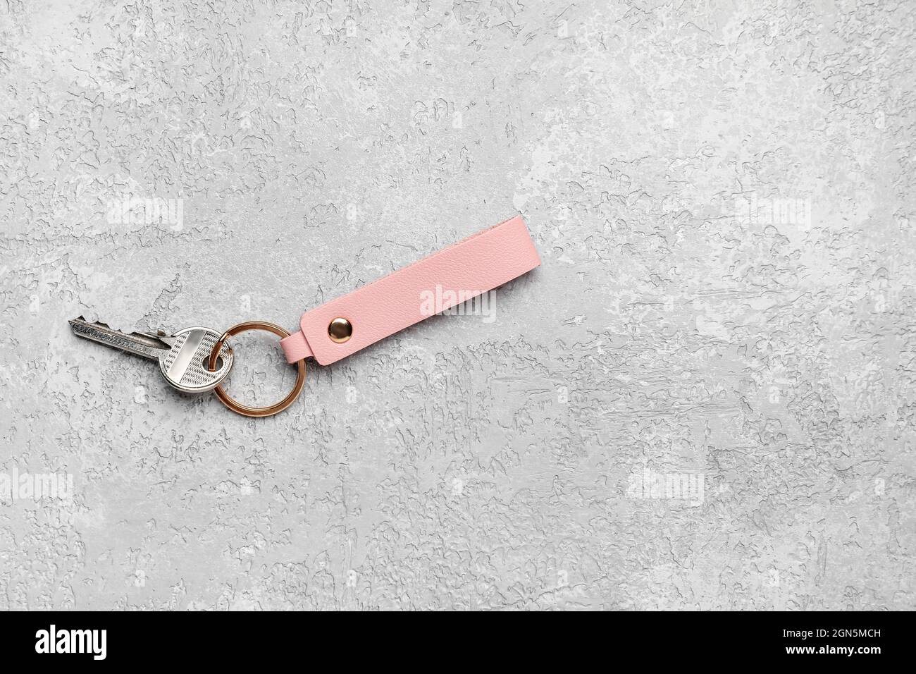 Key with leather keychain on grey background Stock Photo - Alamy