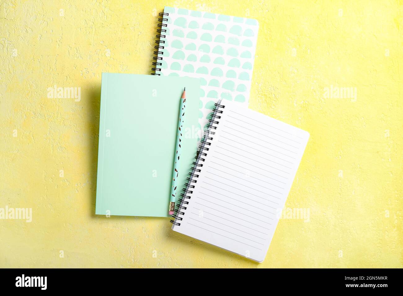 Different notebooks and pencil on color background Stock Photo - Alamy