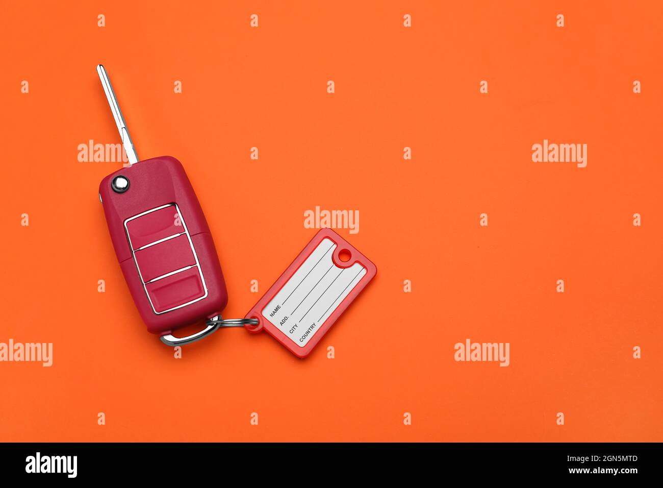 Car key with plastic tag on orange background Stock Photo - Alamy