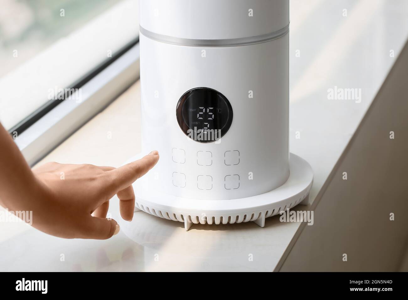 Woman switching on modern humidifier in room Stock Photo - Alamy