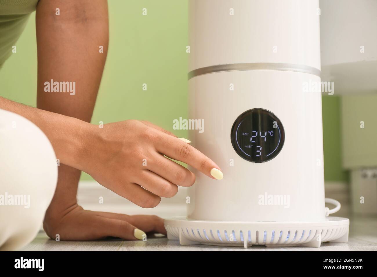 Woman switching on modern humidifier in room Stock Photo - Alamy