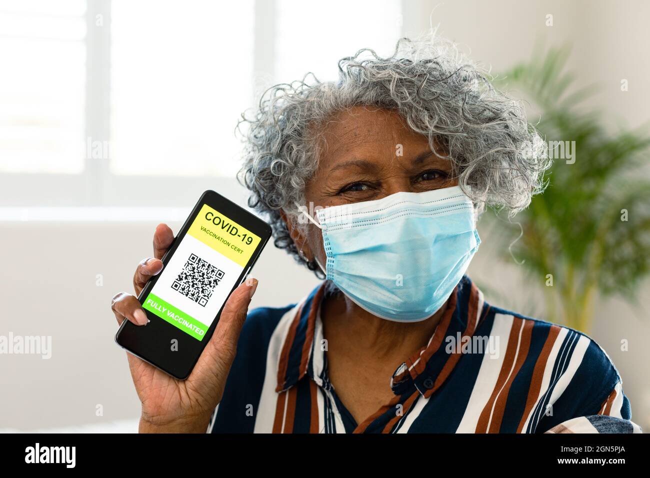 Happy senior african american woman wearing face mask showing covid qr ...