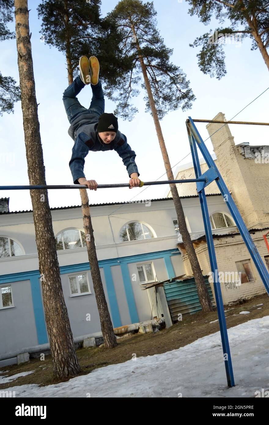 Kovrov, Russia. 12 March 2017. Teen is engaged in discipline gimbarr on a horizontal bar in park ...